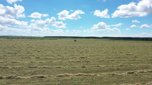 Flying Over Hay Field Towards Tiny Tractor Against Blue Sky with Clouds ...