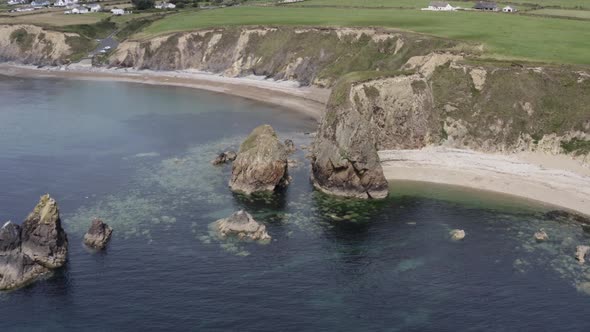 Eroded cliffs and rocky islets and shallow Celtic Sea water, pastures ...