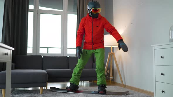 Snowboarder depicts snowboarding on a carpet in a cozy room, Stock Footage