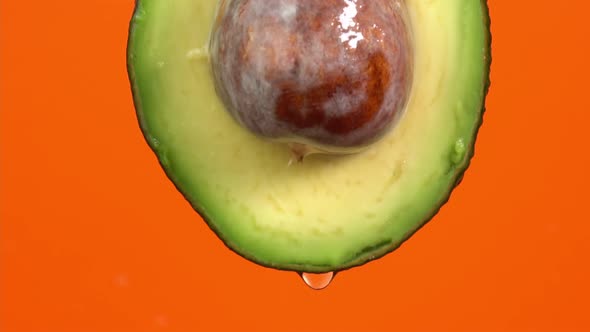 Water drops falling from avocado on orange background. Avocado slice ...