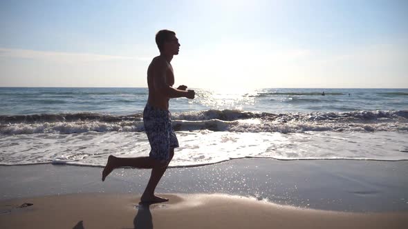Young Sporty Man Running on the Sea Beach at Morning. Athletic Guy ...