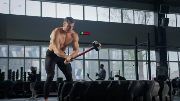 Young male athlete trains in the gym with a hammer, crossfit, endurance ...
