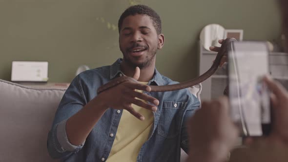 Black Woman Taking Picture of Her Boyfriend Holding Snake at Home ...