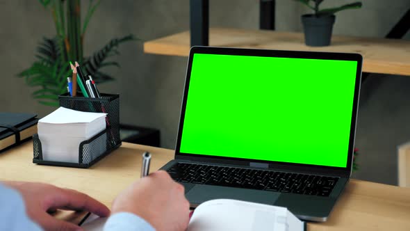 Man student study writes information in notebook. Green screen laptop ...