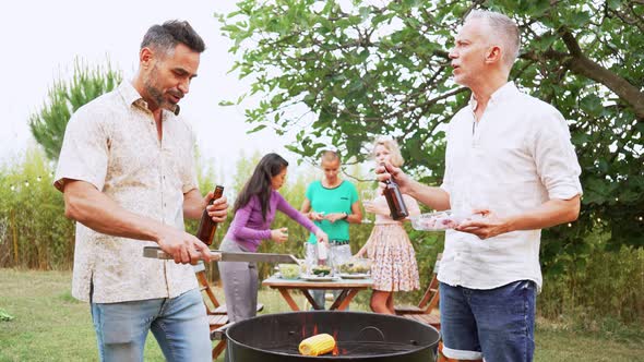 Two Men Cooking and Toasting Beers on a Barbeque in Countryside, Stock ...