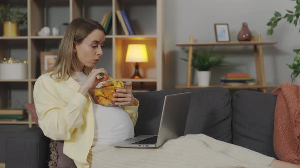 Expectant Mother Watching Film and Eating Snacks at Home, Stock Footage