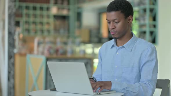 Focused Young African Man Using Laptop in Cafe, Stock Footage | VideoHive