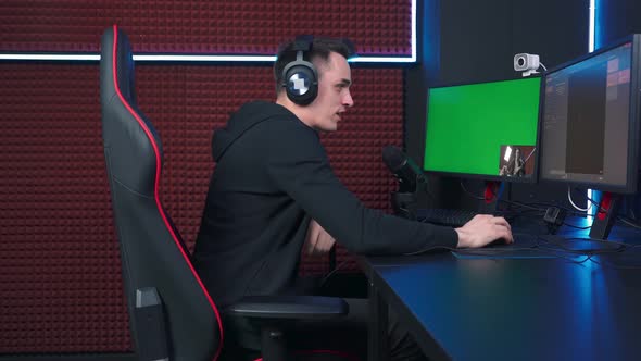 A young streamer sits down in a chair near the computer, puts on ...