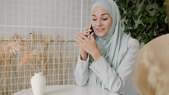 Cheerful Muslimah Chatting on Mobile Phone and Smiling Indoors in Halal ...
