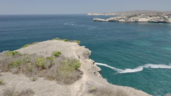 Aerial Shot of Woman Hiking Up the Cliff Overlooking Ocean Water View ...
