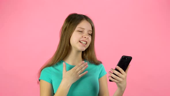 Girl Talking at Video Chatting on Cell Phone in Studio Against Pink ...