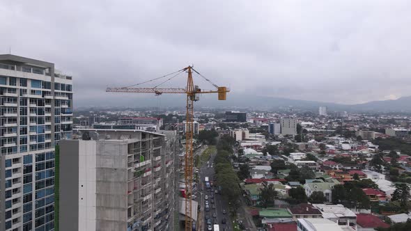 Drone shot of a crane constructing a skyscraper in San Jose city, Costa ...