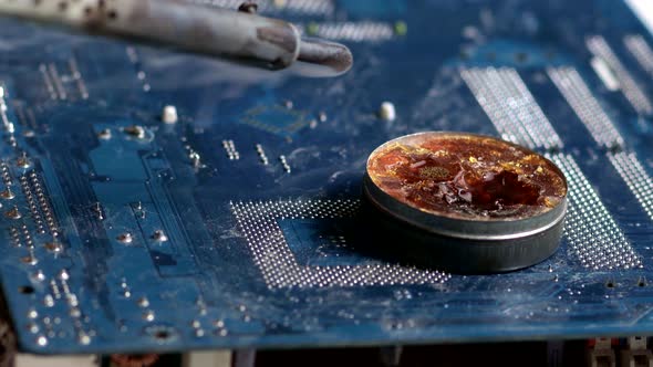 Dunks hot soldering iron in rosin.Motherboard smartphone.Preparing to ...