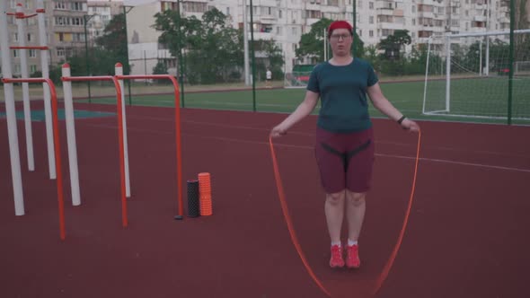 Fat Woman Jumping Rope to Lose Weight on an Outdoor Gym by fotoliza