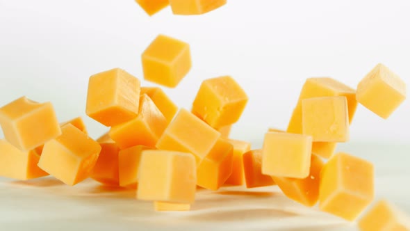 Super Slow Motion Shot of Cheese Chunks Falling on White Background at ...