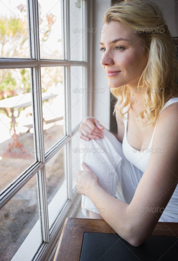 Pretty blonde looking out the window at home in the living room Stock ...