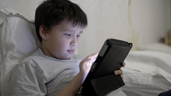 Teenager Boy Using Tablet Computer Lying In Bed, Stock Footage | VideoHive