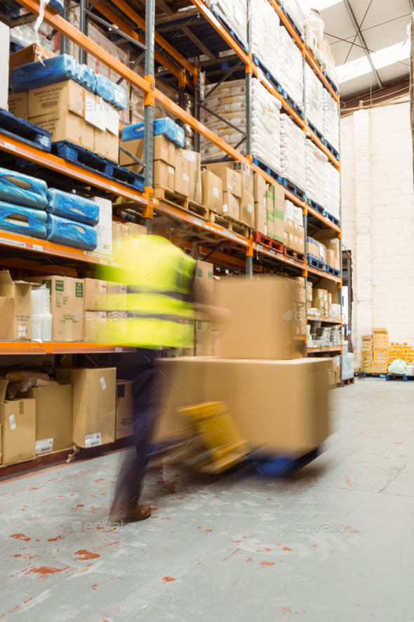 Worker pushing trolley with boxes in a blur in a large warehouse Stock ...