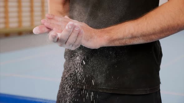A sportsman is dusting hands with sport magnesia, close-up of arms ...