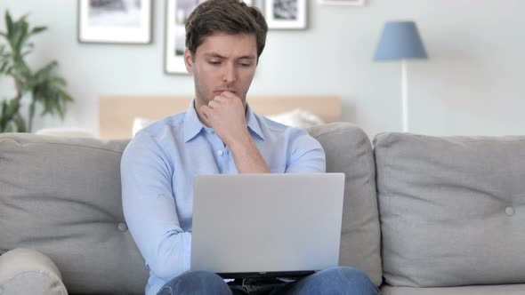 Man Thinking and Working on Laptop while Sitting on Couch, Stock Footage