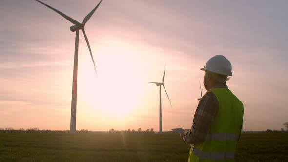 Windmill Engineer Watching Wind Turbines in Operation on a Tablet ...