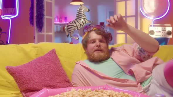 Man in 90s Party Outfit Lying on Sofa and Eating Popcorn, Stock Footage