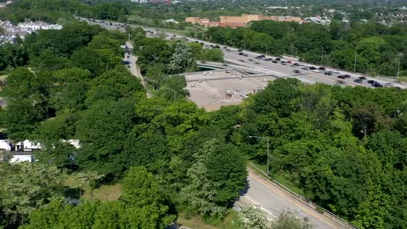 An aerial time lapse over a park with green trees, a parkway with ...