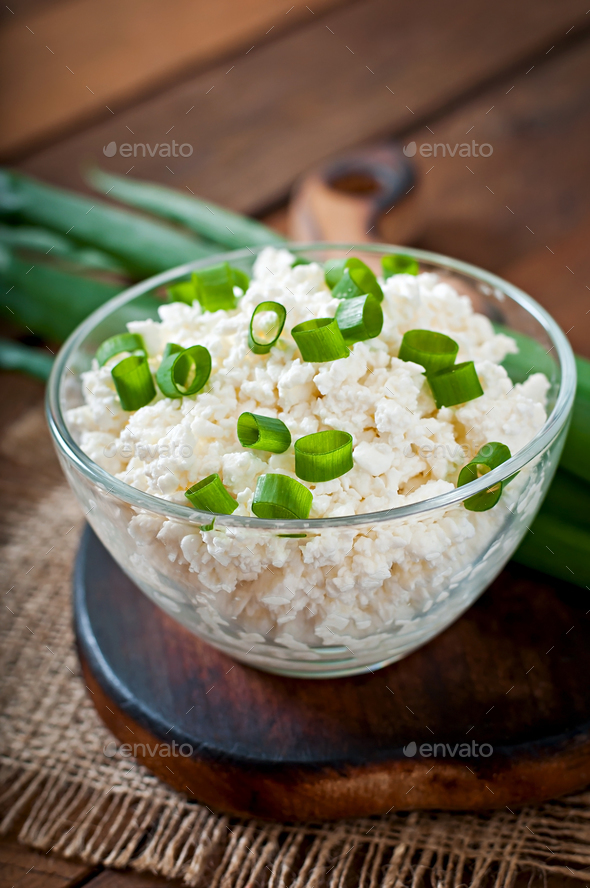 Useful cottage cheese with chives in a glass bowl on a wooden ...