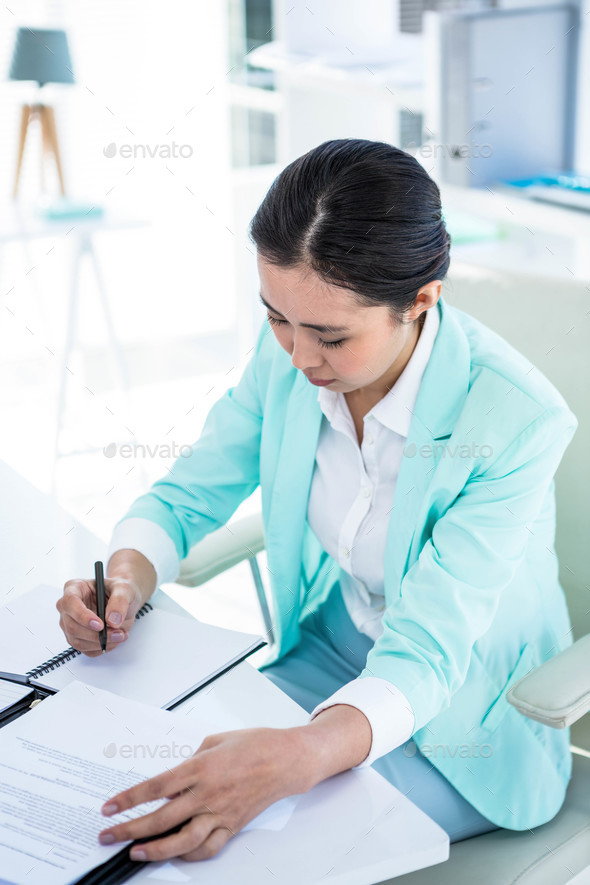 Smiling businesswoman writing into a notepad at the desk in work Stock ...