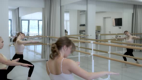 Three young girls dance in a white bright studio in front of a mirror ...