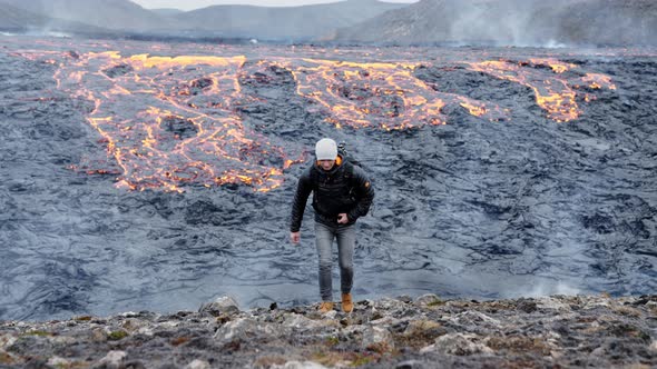 Man Taking Off Rucksack As Lava Flows Behind Him, Stock Footage | VideoHive