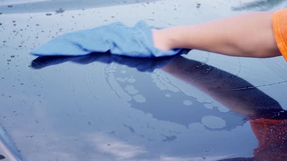 Hand of worker man using microfiber wiping water droplets to dry black ...