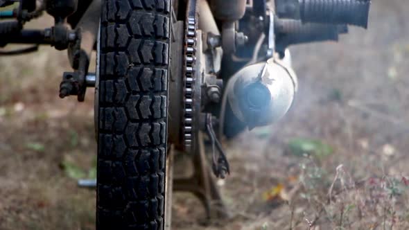 An old rusty motorcycle in oil that emits exhaust gases into the air ...