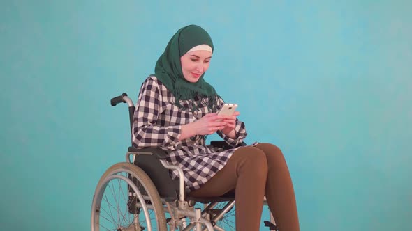 Young Muslim Woman Disabled Person in a Wheelchair Uses the Phone on a ...