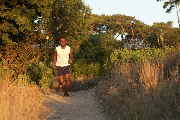 Fit young man running on path outdoors Stock Photo by mimagephotography