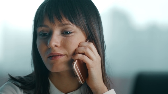 Young Woman Laughing On The Phone Sitting At Her Desk In An Office ...