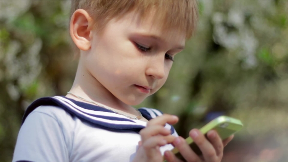 Young Little Boy Plays Games On Smartphone. Spring Park, Stock Footage
