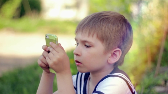 Young Little Boy Plays Games On Smartphone. Spring Park 4, Stock Footage