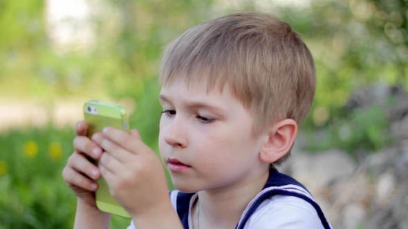 Young Little Boy Plays Games On Smartphone. Spring Park 3, Stock Footage