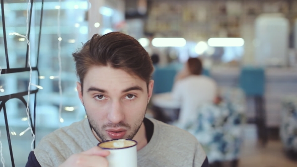 Young Man Looking At The Camera And Drink Coffee In Cafe, Stock Footage