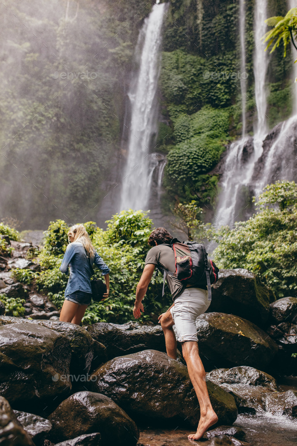 Couple crossing a stream together in the forest Stock Photo by jacoblund