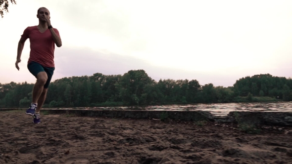 Male Runner In Red Tshirt Running Along Sandy Riverside, Stock Footage