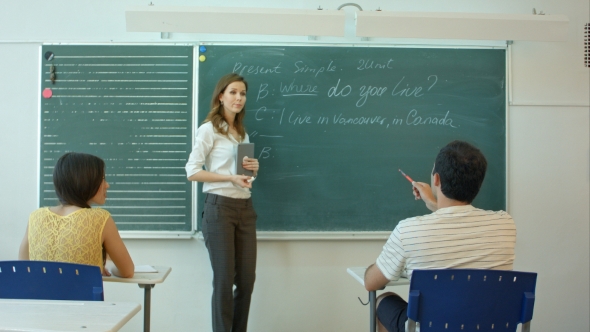 Young Female Teacher Writing On Chalkboard In Class, Stock Footage