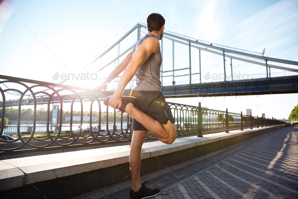 Side view of a sports man stretching with bridge railing Stock Photo by ...