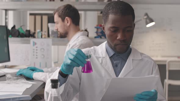 African American Chemist Analyzing Purple Substance in Glass Flask ...