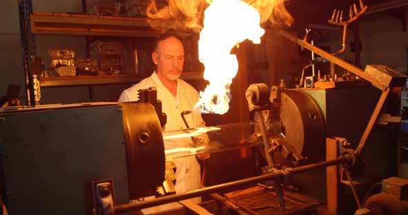 Mature male worker lighting glass blowing torch in glass factory 4k ...