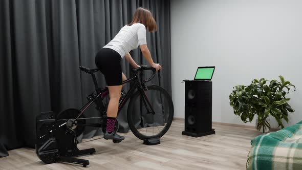 Indoor Virtual Cycling, Fit cycling woman rides bicycle at home on ...