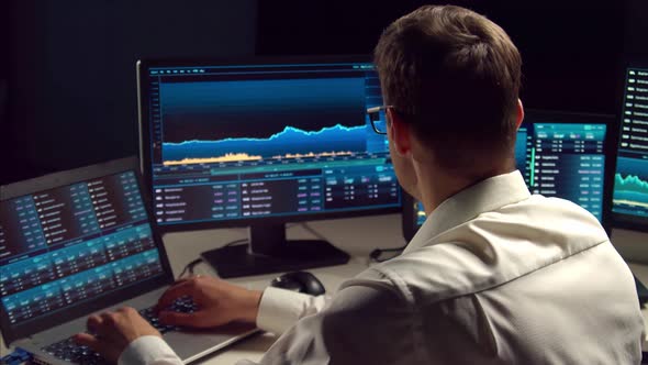 Trader working in office at night using workstation and analysis ...