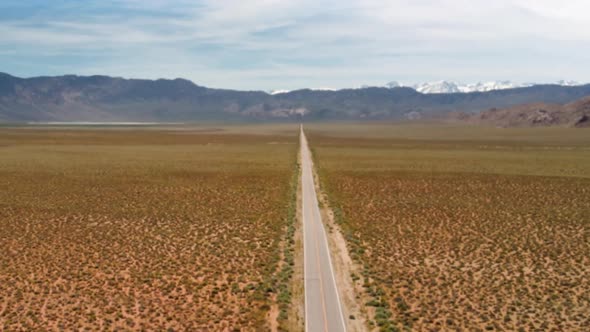Warped Hyper Lapse of Clouds Over Long Desert Road with Snowy Mountains ...