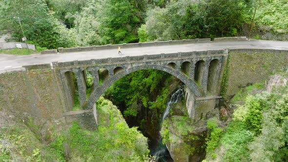 Person crossing ancient arch bridge, A Ponte Velha, Madeira; aerial ...